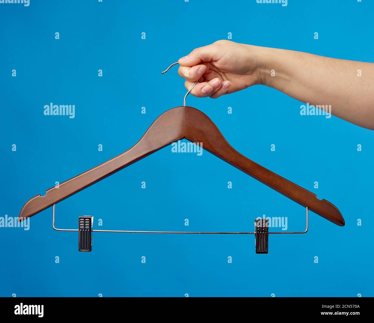 female hand holds empty brown wooden hanger Stock Photo - Alamy