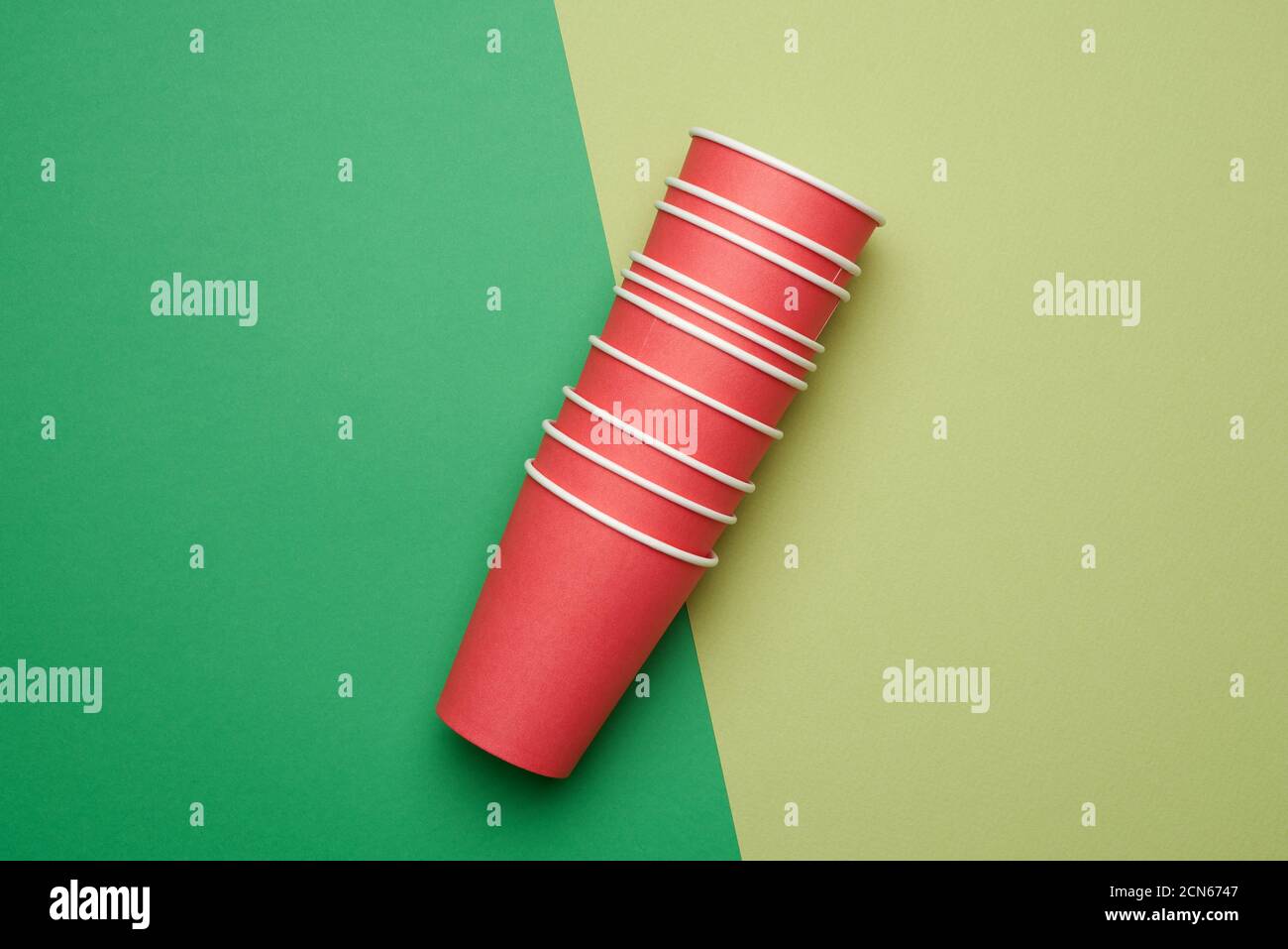 stack of red paper disposable cups on a green background, flat lay ...