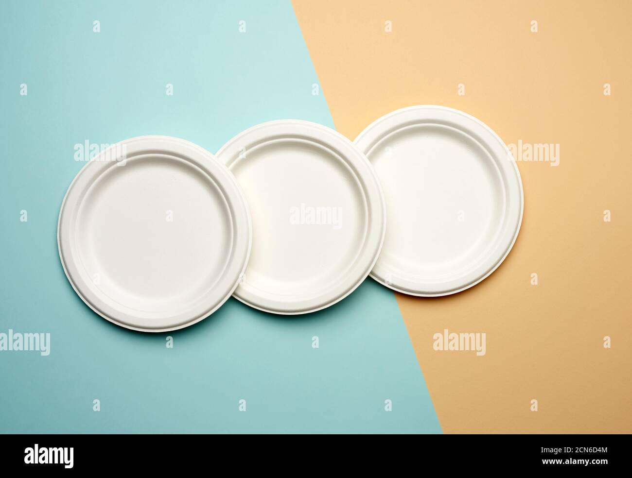 stack of white paper disposable plates on a beige-blue background, top ...
