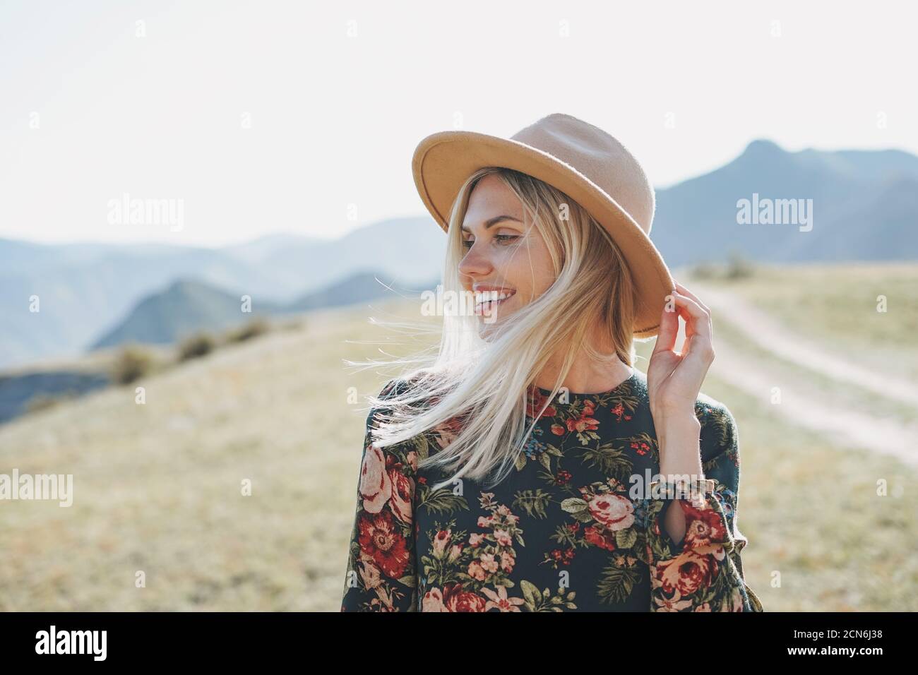 Beautiful smiling blone young woman traveler in dress and felt hat on ...