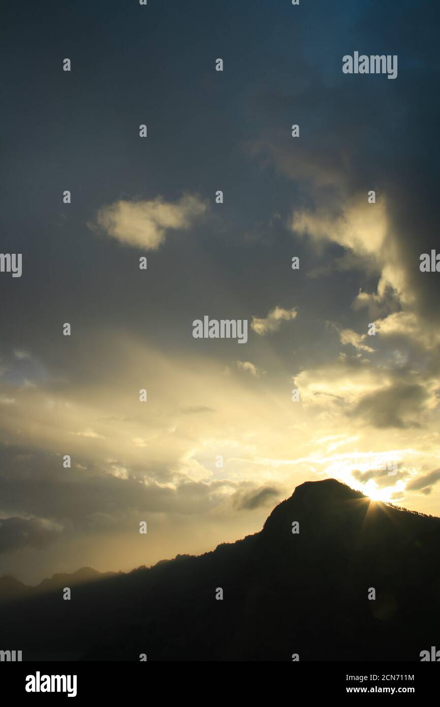 Yellow sunset behind mountain cliff Stock Photo - Alamy