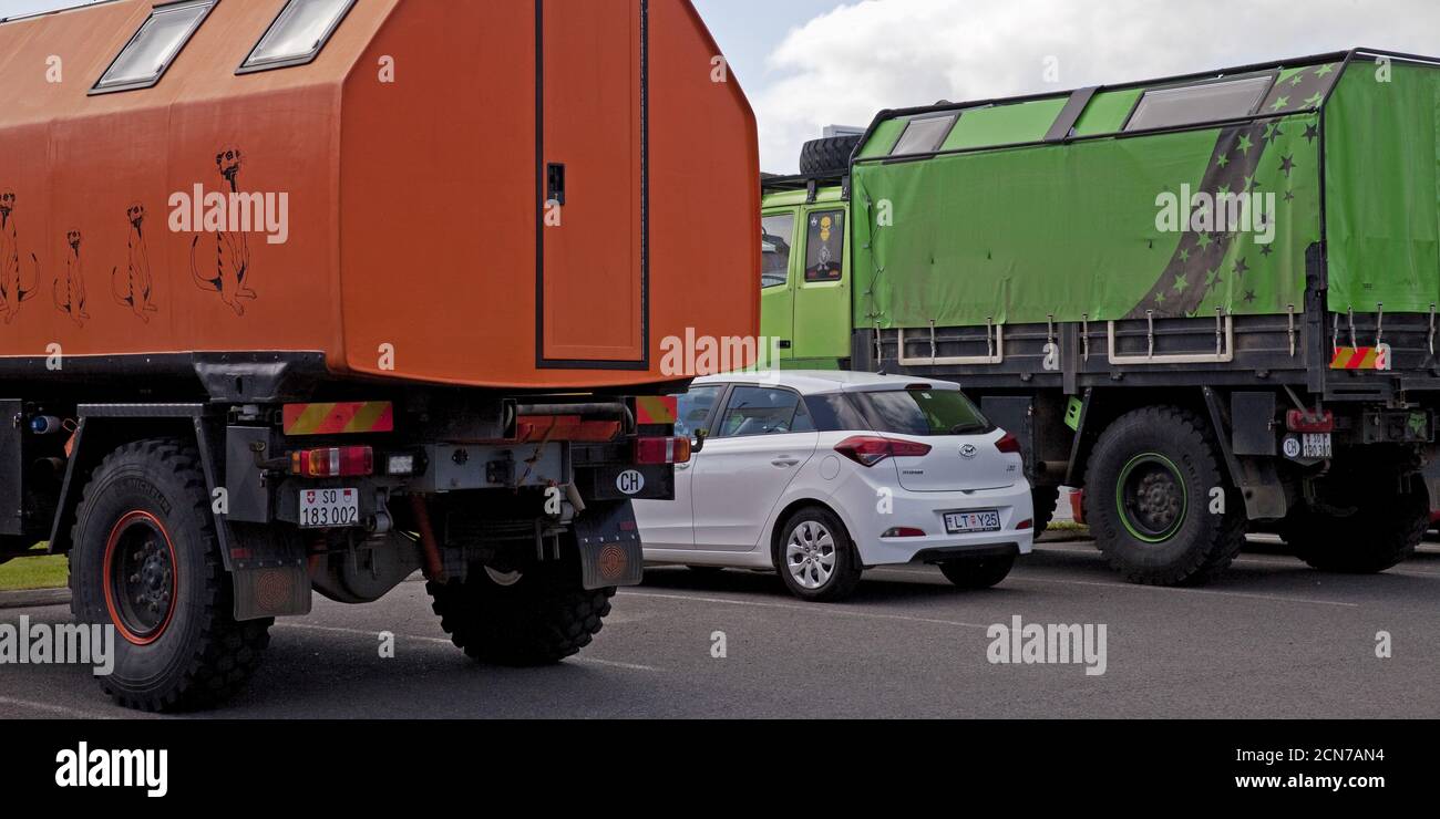 Normal car between two expedition vehicles in a parking lot ...