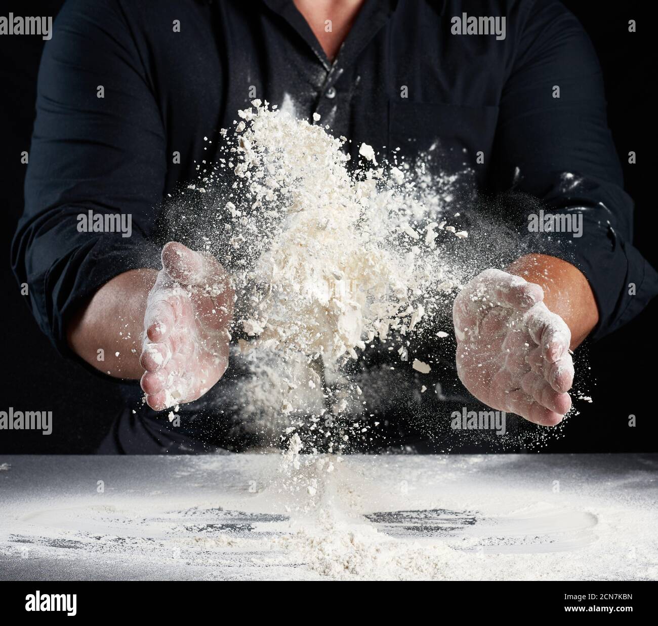 chef in black uniform sprinkles white wheat flour in different ...
