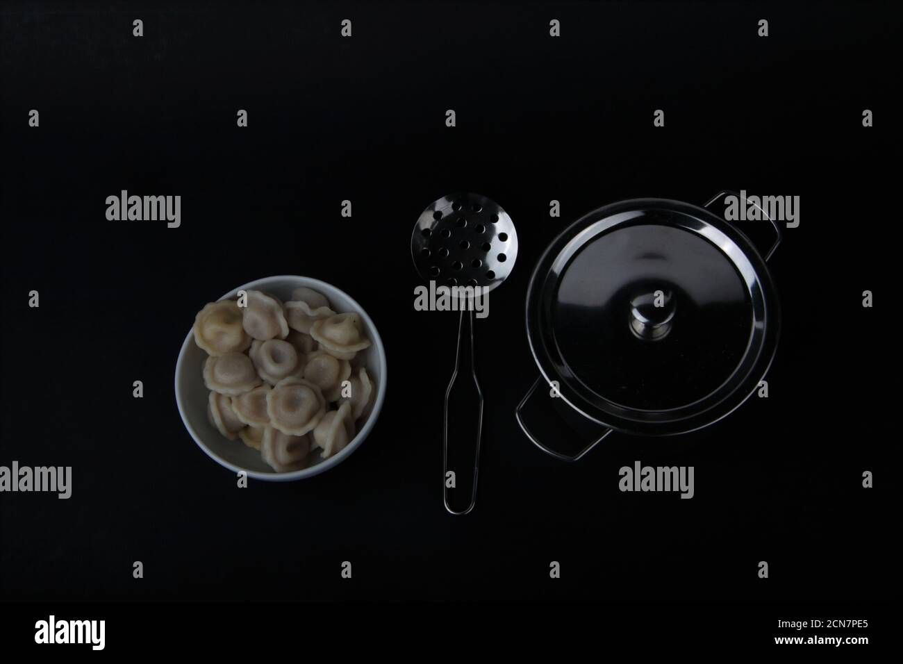 Uncooked russian pelmeni and flour on black background flat lay ...
