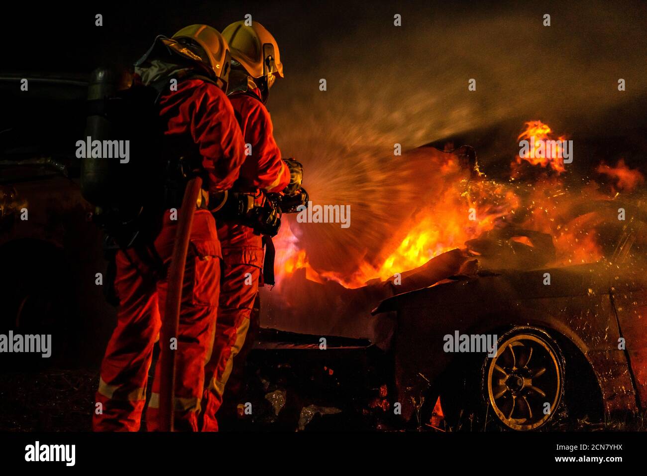 Firefighters spraying down fire flame from car accident Stock Photo - Alamy