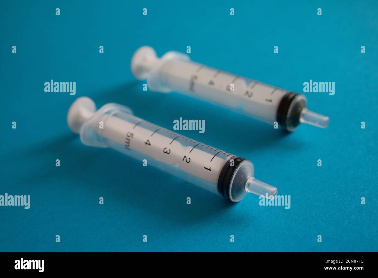 Injection with two syrings on blue paper Stock Photo - Alamy