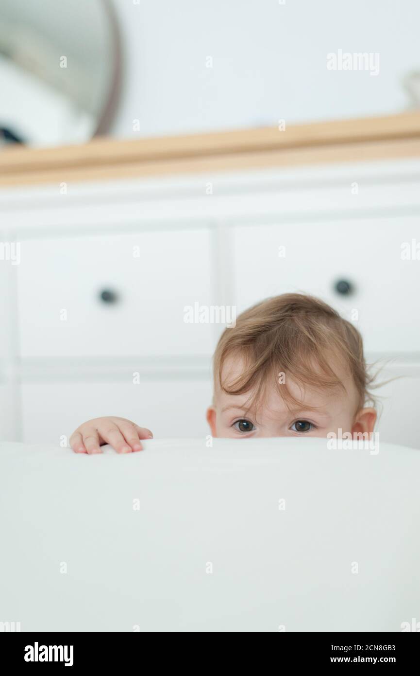 Little girl looking over bed Stock Photo - Alamy