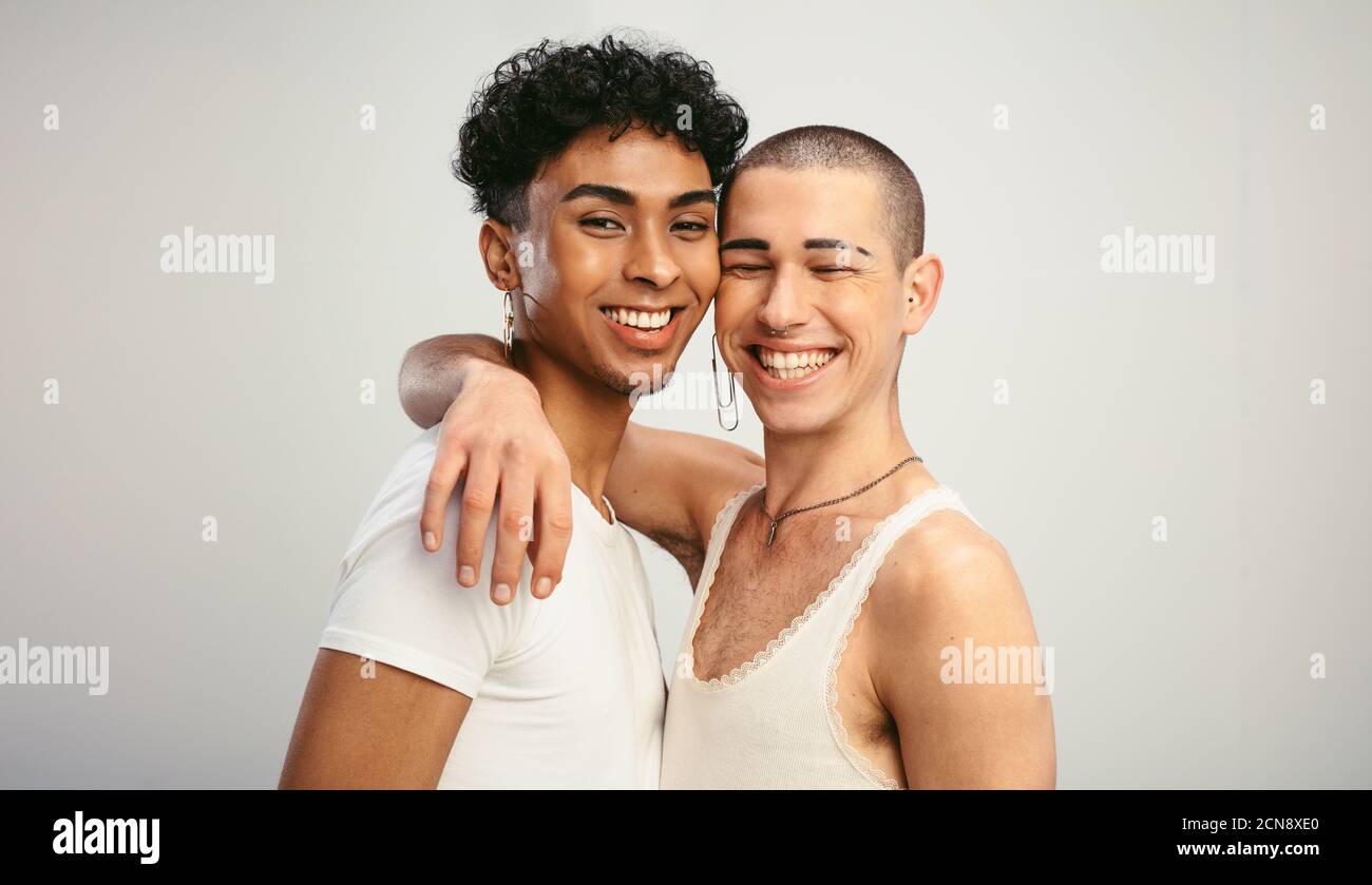 Cheerful male couple smiling on white background. Two men standing ...