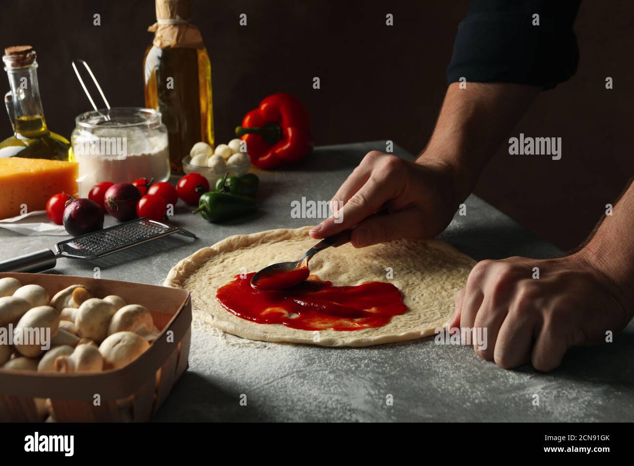 Man cooking pizza on gray table with ingredients Stock Photo - Alamy