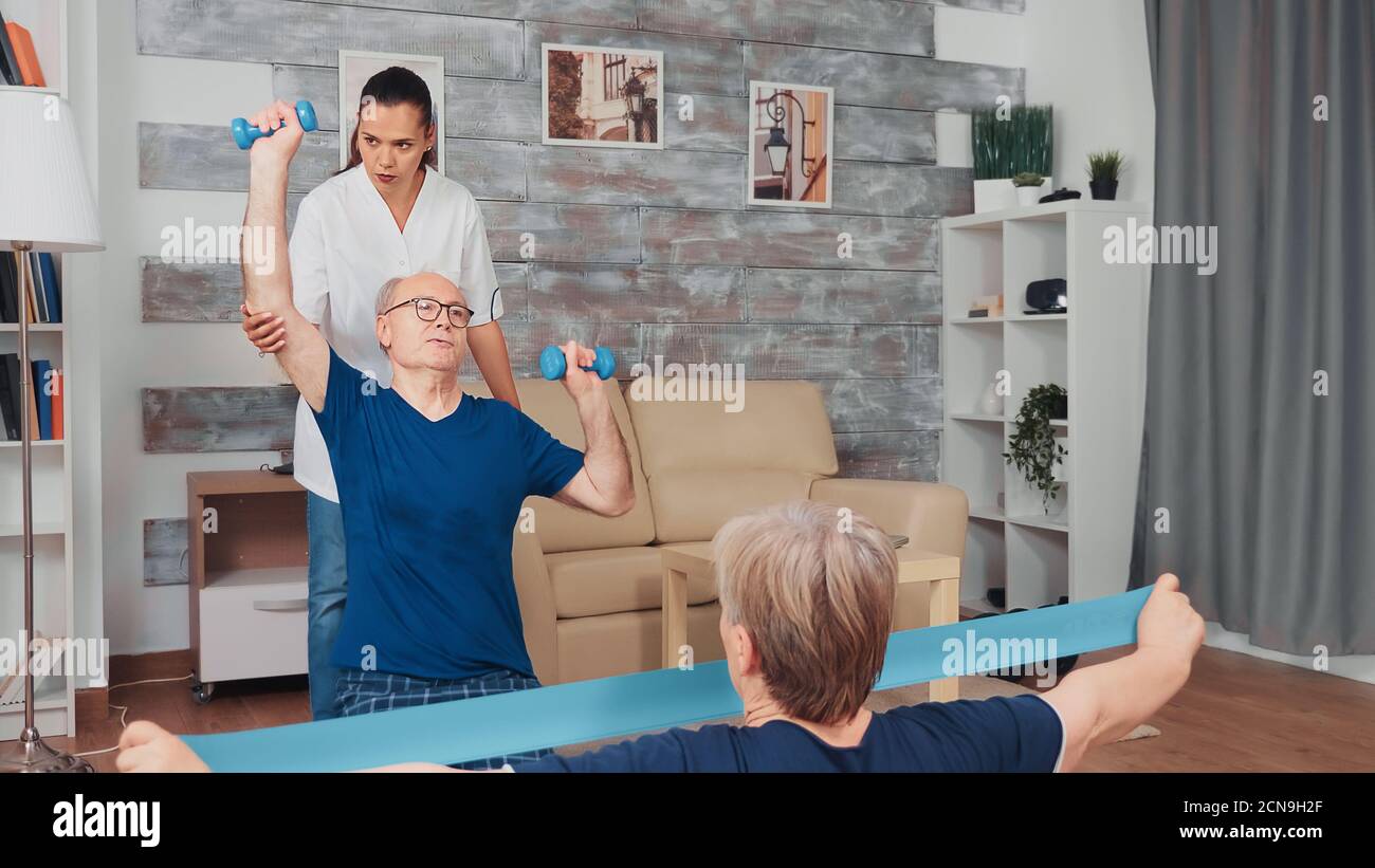 Nurse doing physical therapy with senior couple. Home assistance ...