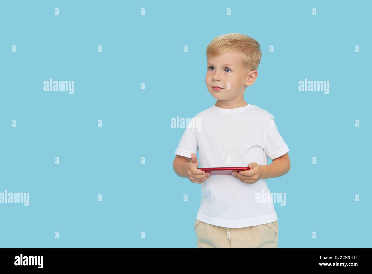 Cute smilling child boy with smartphone on blue background. Advertising ...
