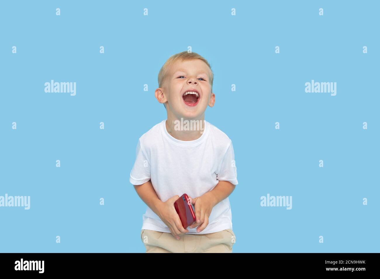Cute smilling child boy with smartphone on blue background. Advertising ...