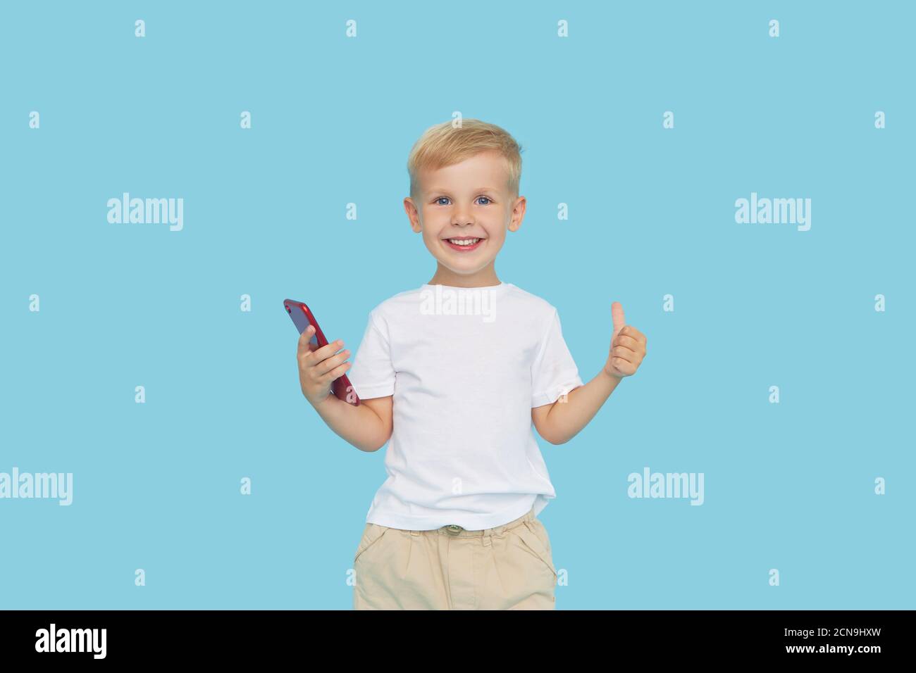 Cute smilling child boy with smartphone on blue background. Advertising ...