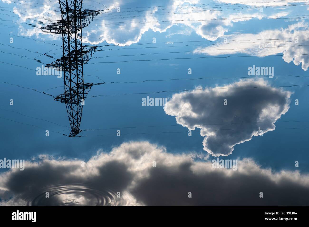 Reflection of a power line and dark cumulus clouds in the water on a ...