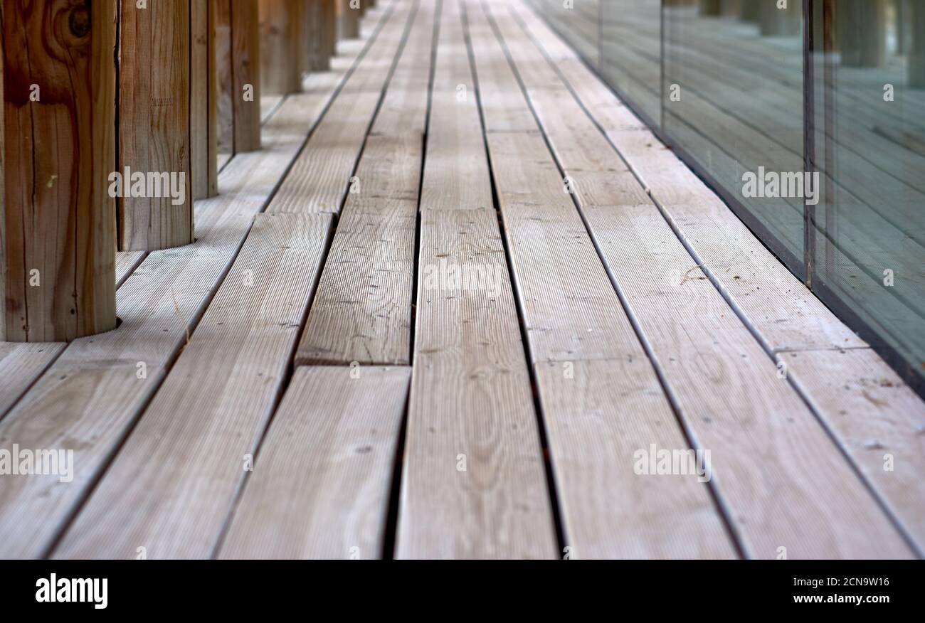 detail of a wooden walkway flanked by wooden pillars and a glass wall ...