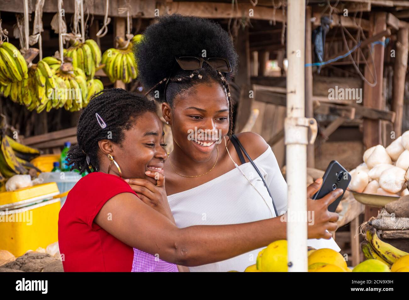 women in a local african market viewing content on a phone together ...