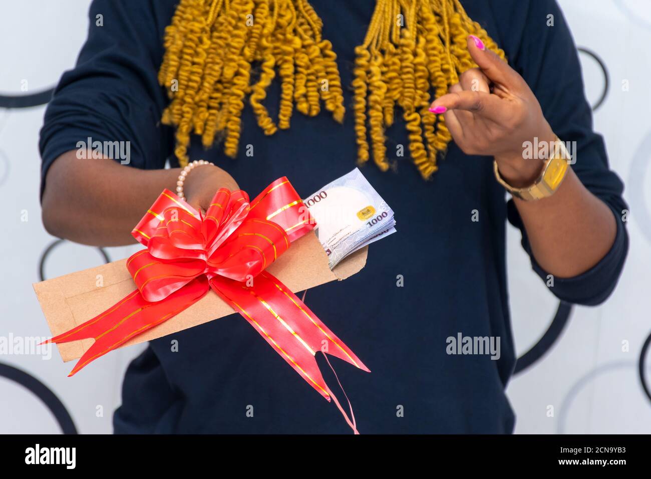 lady stretches forward an envelope wrapped with a red ribbon containing ...