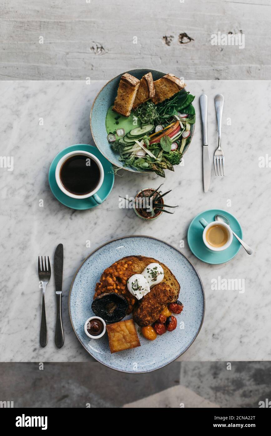 Full English breakfast and greens on toast on restaurant table Stock ...