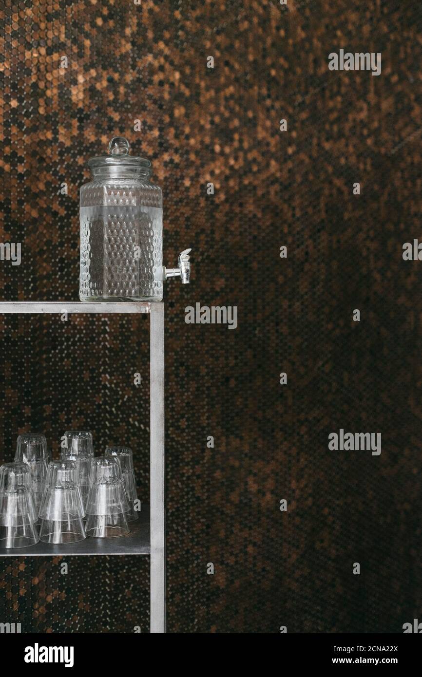 Water dispenser and glasses on restaurant shelves Stock Photo - Alamy