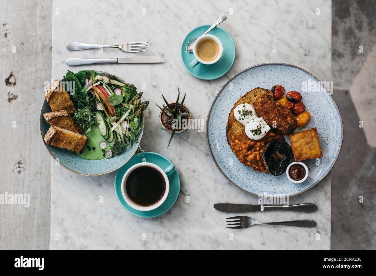Full English breakfast and greens on toast on restaurant table Stock ...