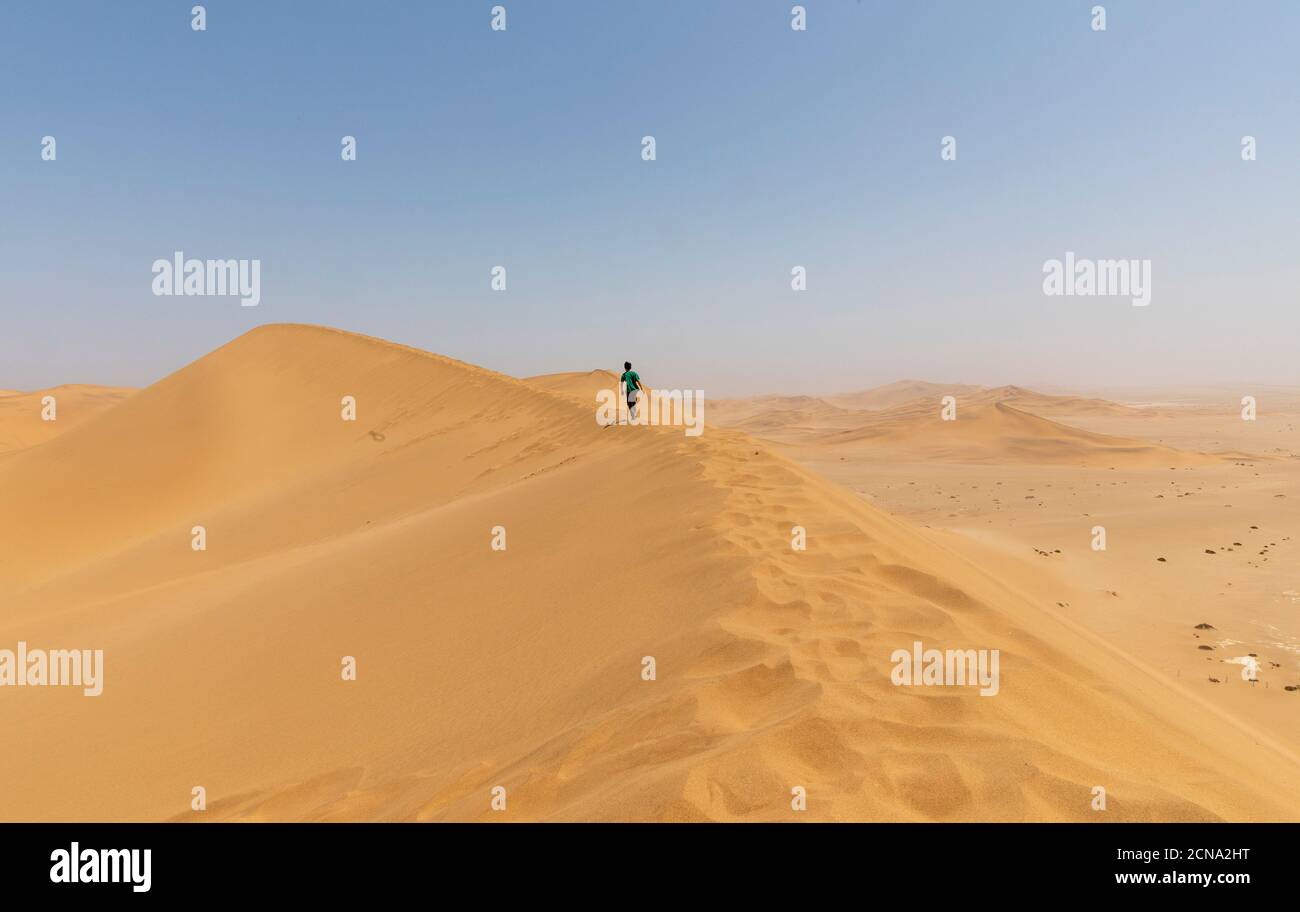 Boy walking along sunny desert sand dune ridge, Namibia Stock Photo - Alamy