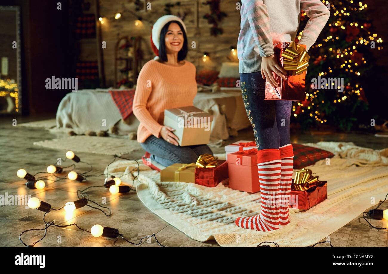 Girl hiding gift behind back while in Christmas Stock Photo - Alamy