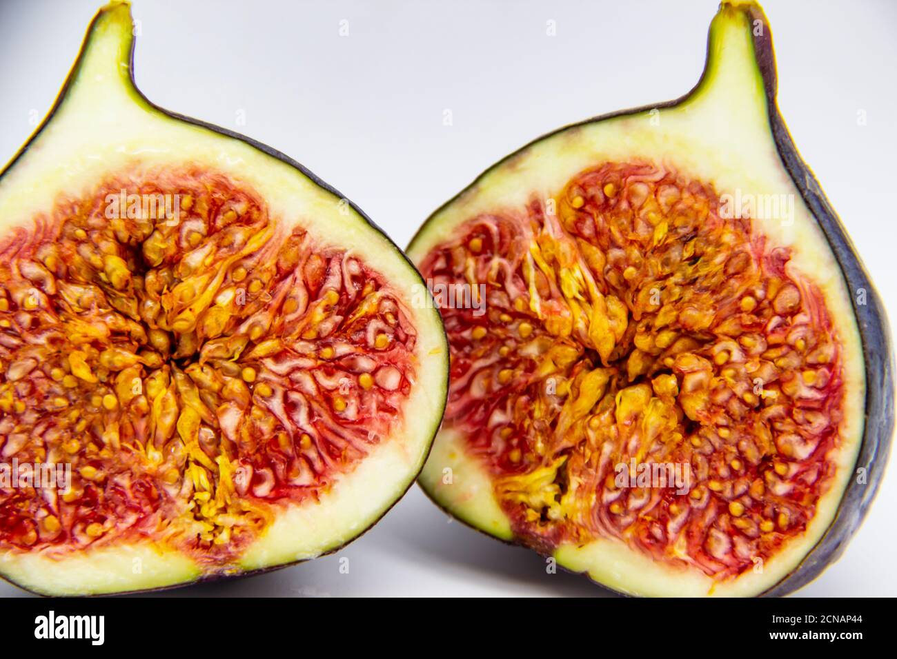 Two halves of figs isolated on a white background. View of ripe purple ...