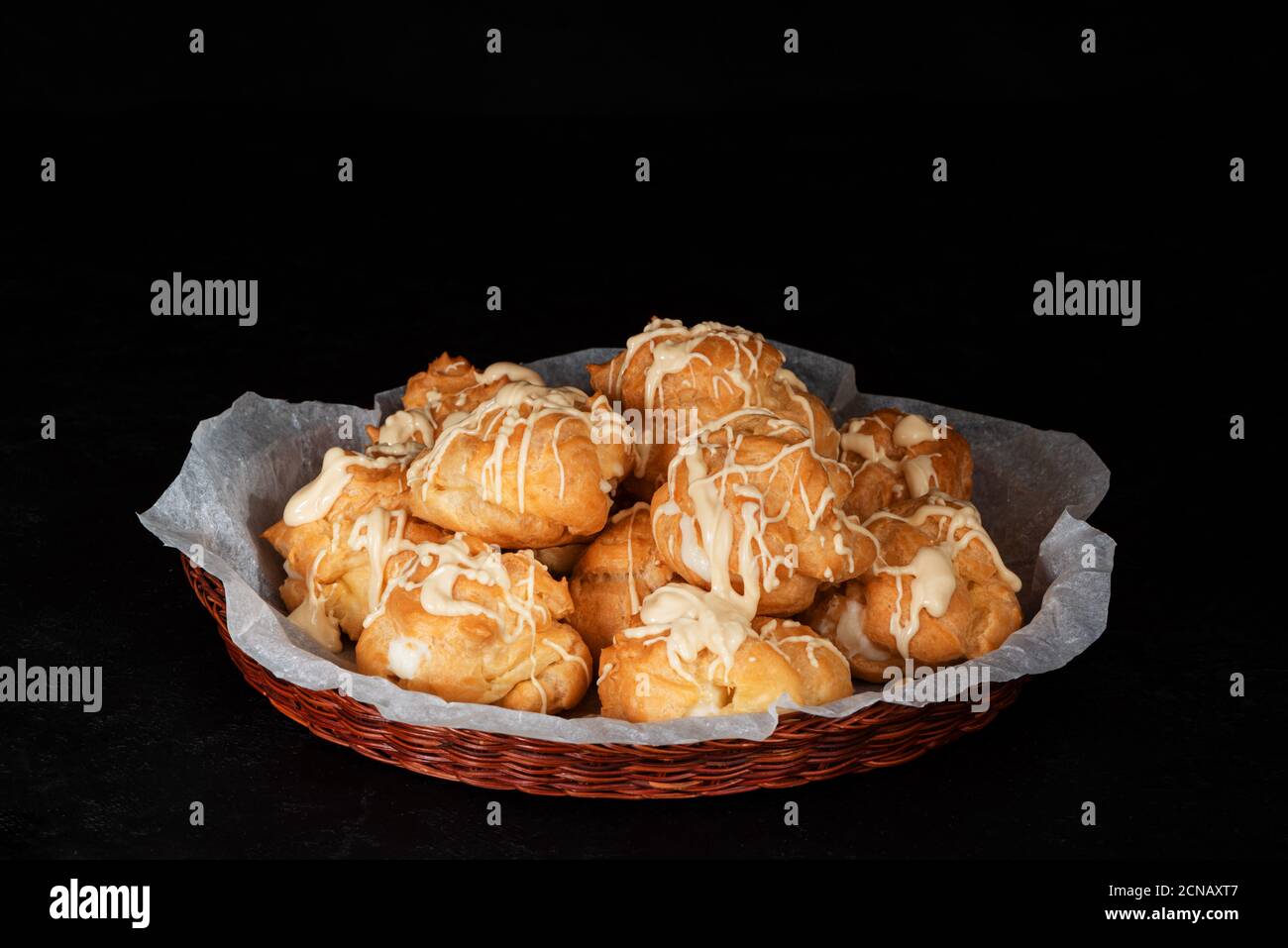 Homemade profiteroles with custard cream topped with white melted ...