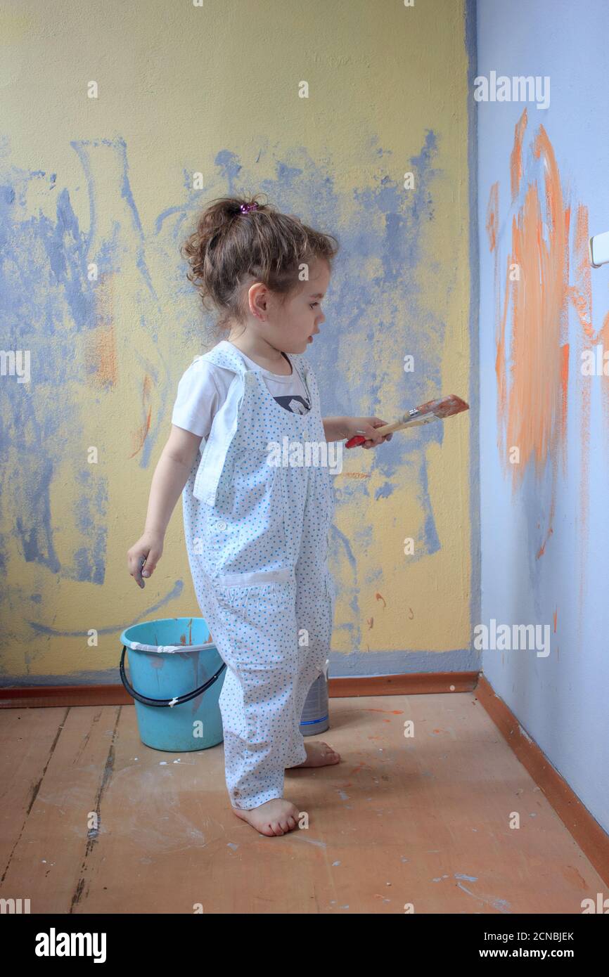 Little kid having fun with paint brush, helping renovating walls by ...