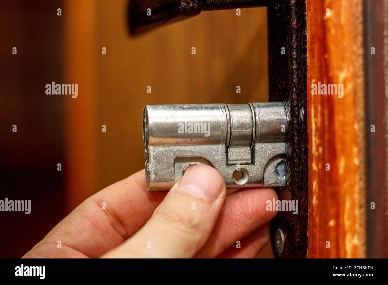 Locksmith installs new door lock into wooden door Stock Photo - Alamy