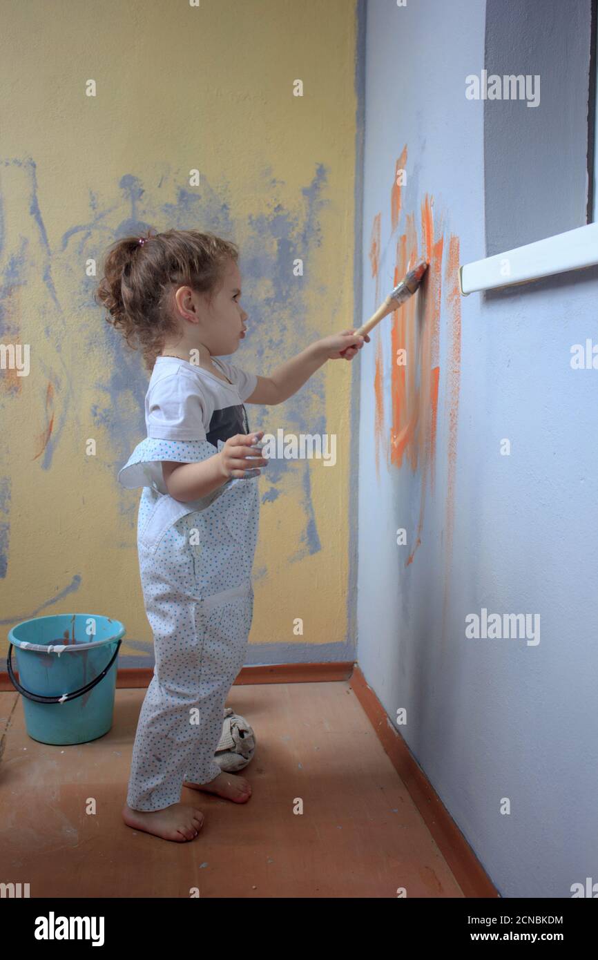 Little kid having fun with paint brush, helping renovating walls by ...
