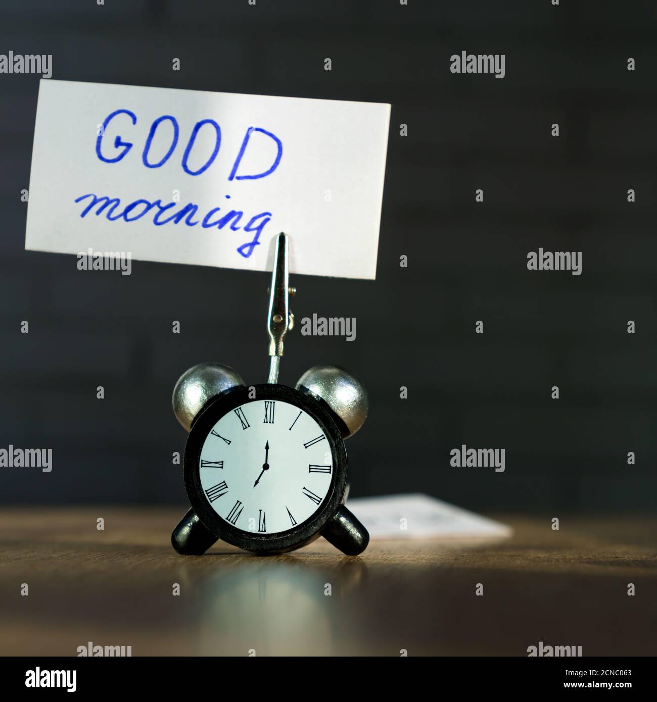 Alarm clock and banner with handwritten phrase"good morning" on wooden ...