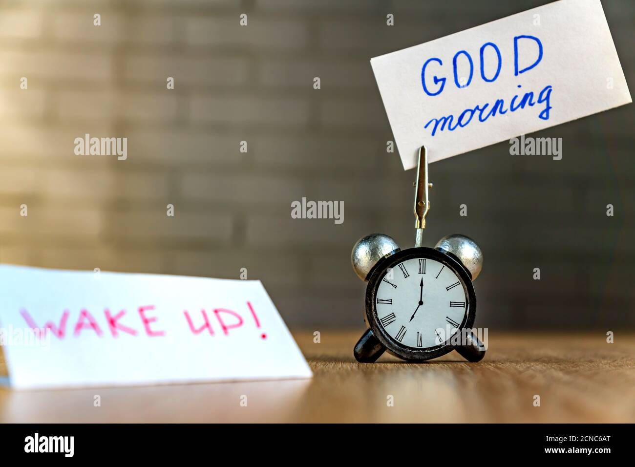 Alarm clock and banner with handwritten phrase"good morning" on wooden ...