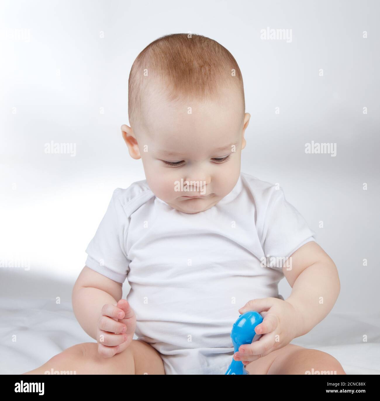 Photo of a ten-month-old baby boy looking at blue rattle Stock Photo ...