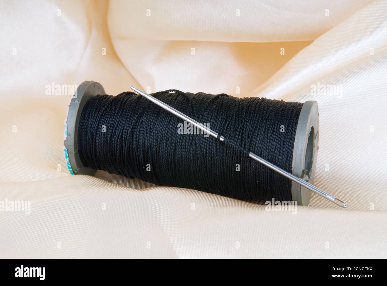 Spool of black thread with a needle and buttons Stock Photo - Alamy