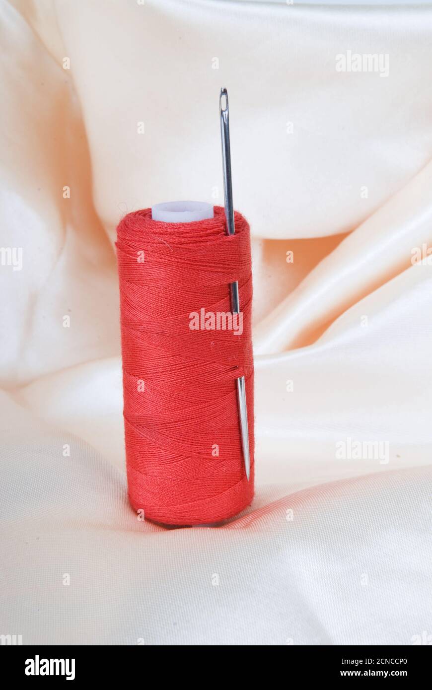 Spool of red thread with a needle Stock Photo - Alamy