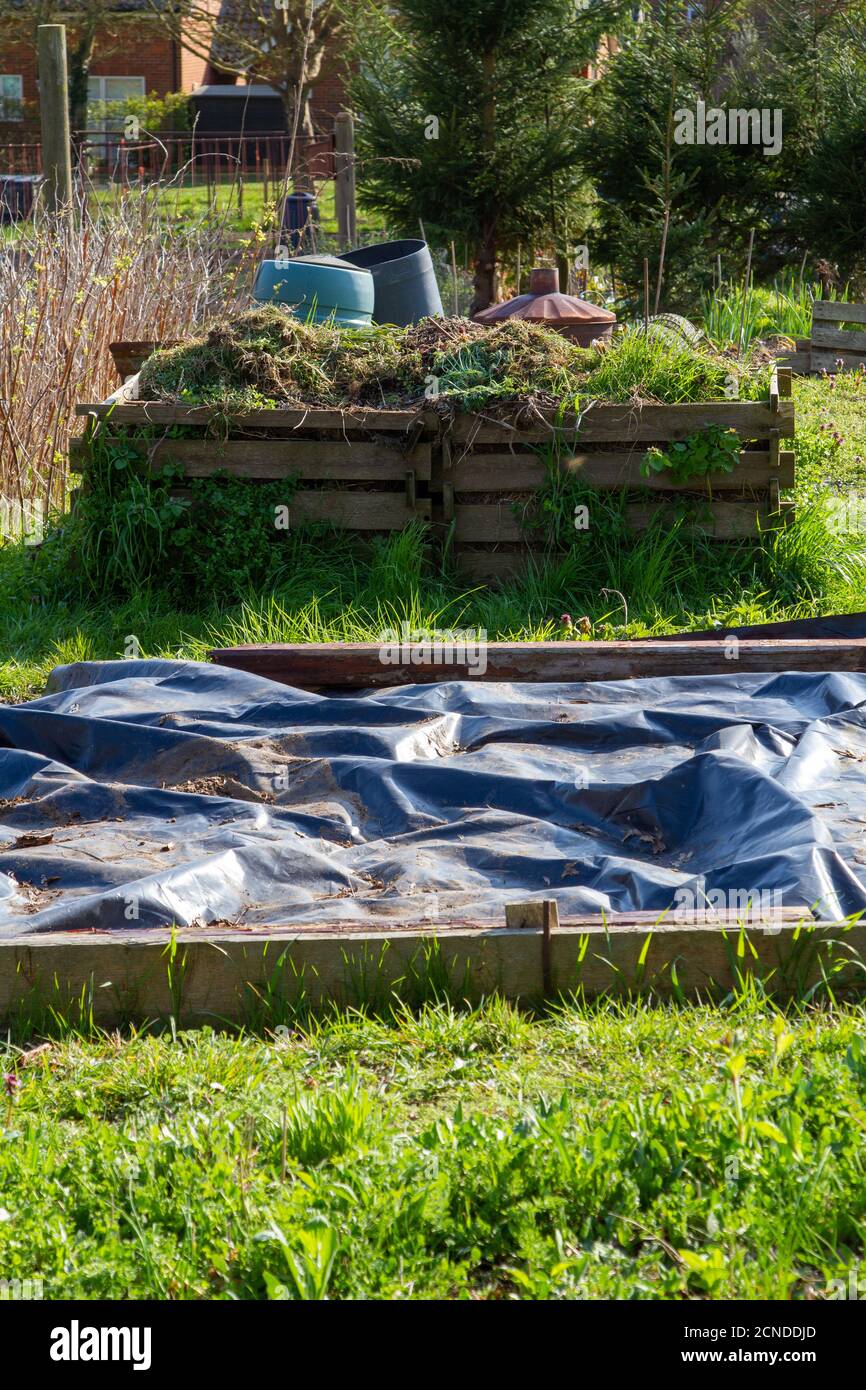 Compost bins and a plastic covered raised bed standing by in an ...