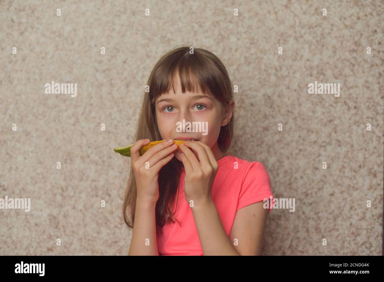 Portrait of girl biting melon. Girl eating melon. Teenager in pink t ...