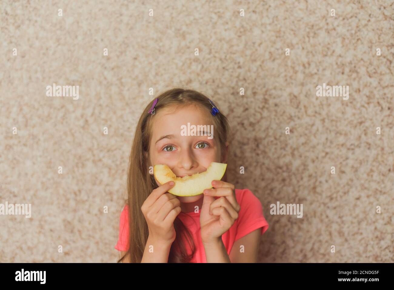 Portrait of girl biting melon. Girl eating melon. Teenager in pink t ...