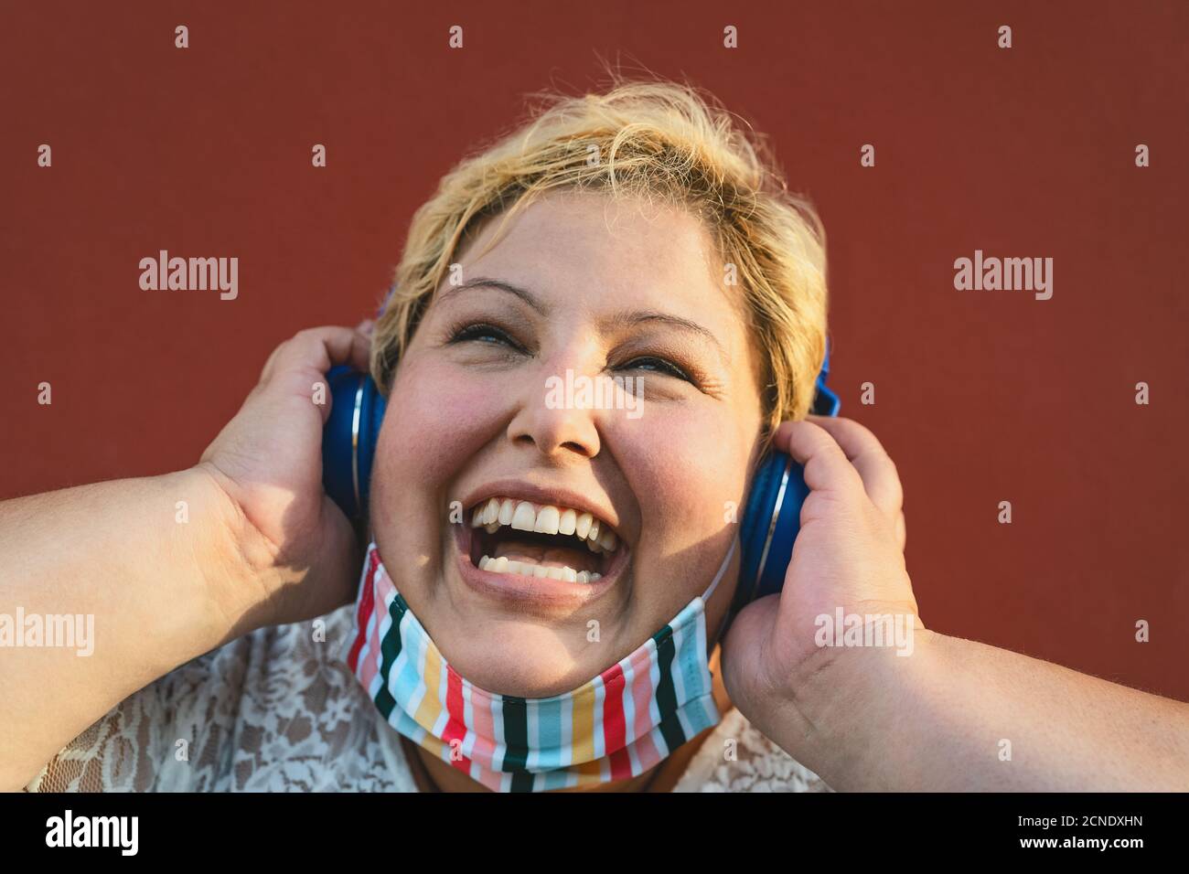 Plus size woman listening to music playlist with wireless headphones ...