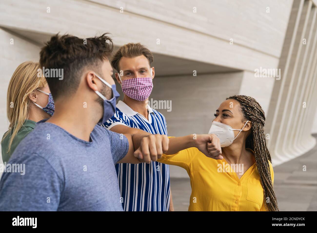 Young friends wearing face protective mask doing new social distancing ...