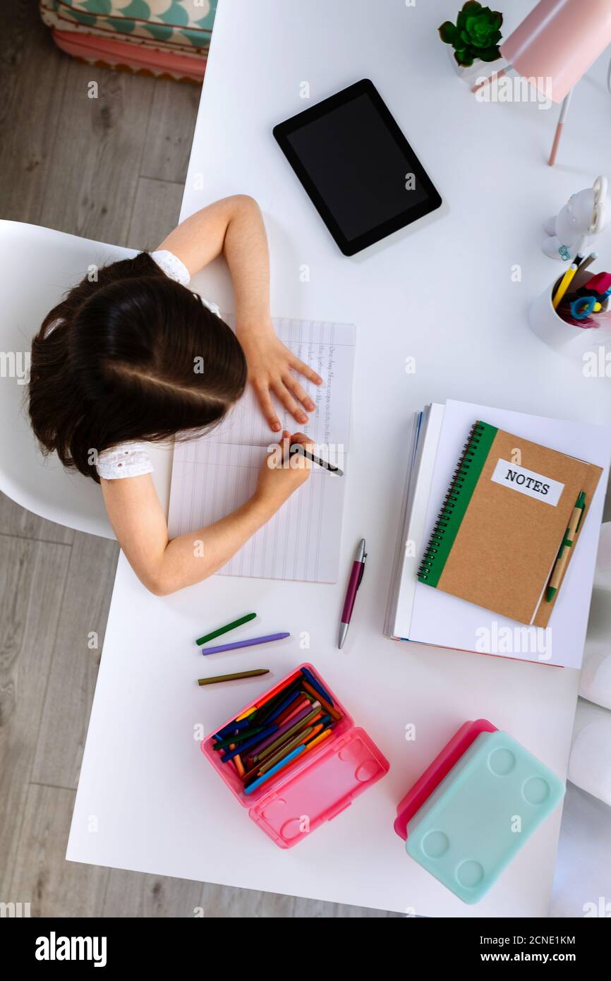 Girl doing homework sitting at a desk Stock Photo - Alamy
