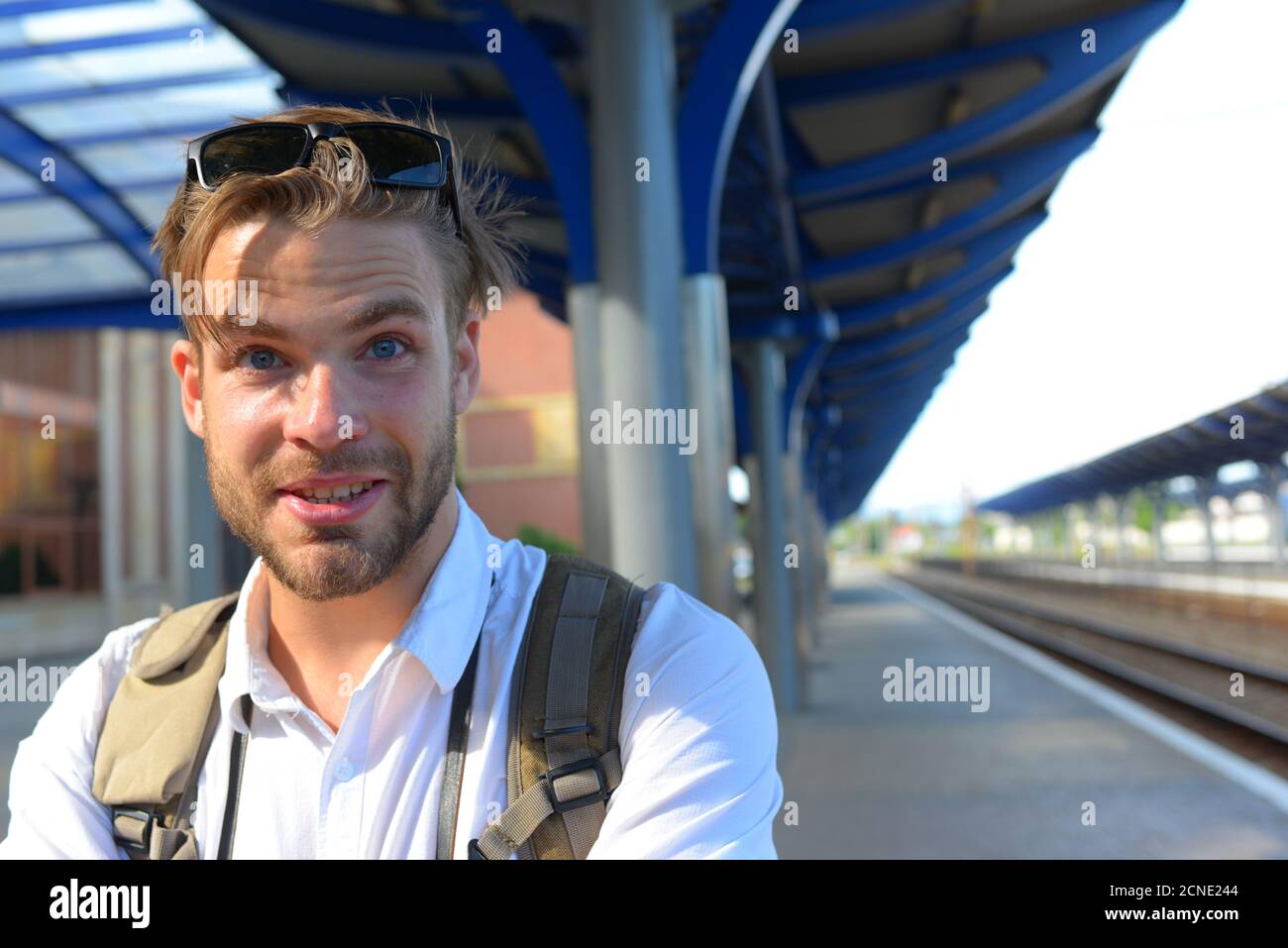 Guy with sunglasses waits for train, defocused. Young man standing on ...