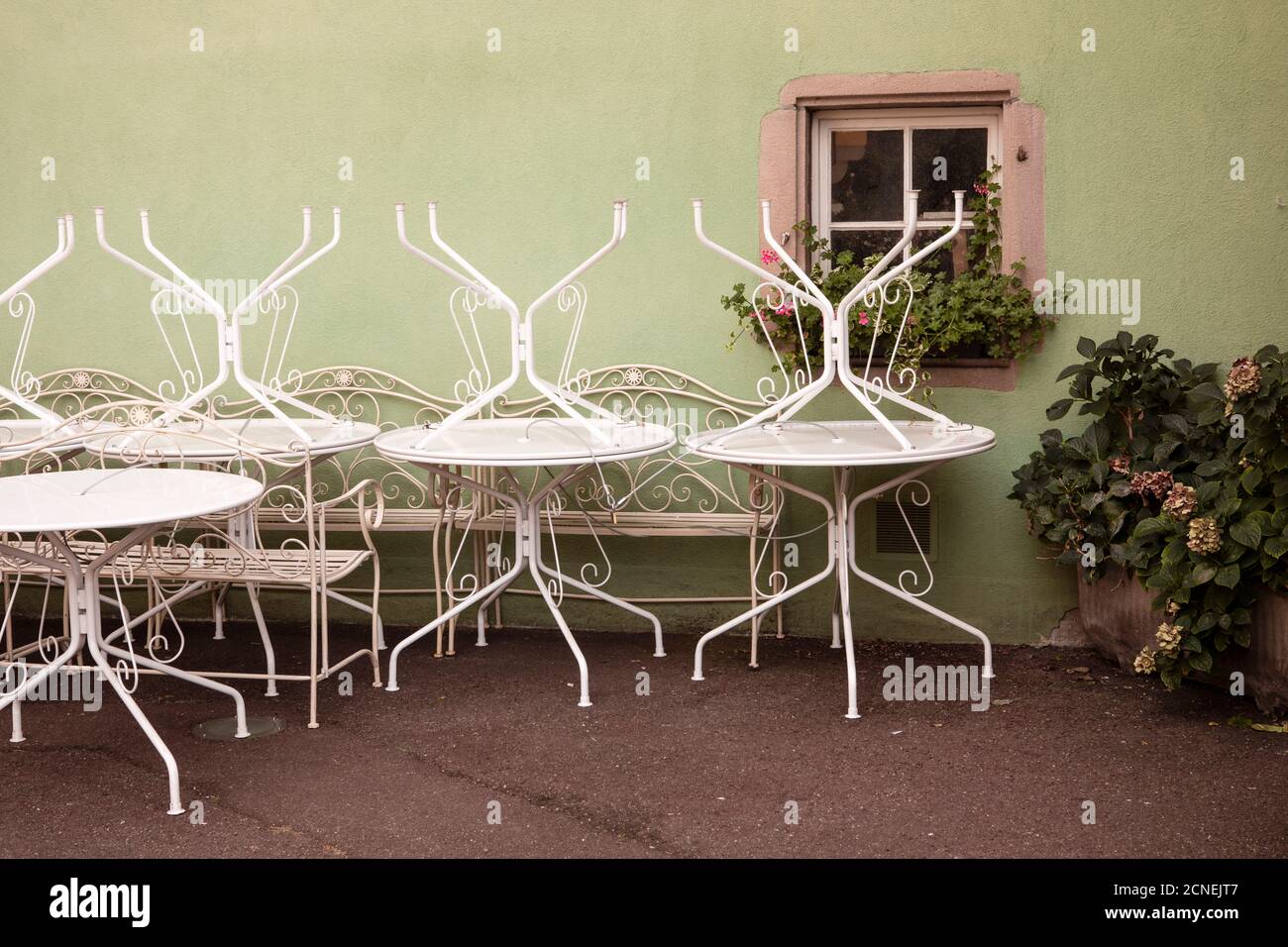 Vintage style white tables upside down in closed restauSrant. Green ...