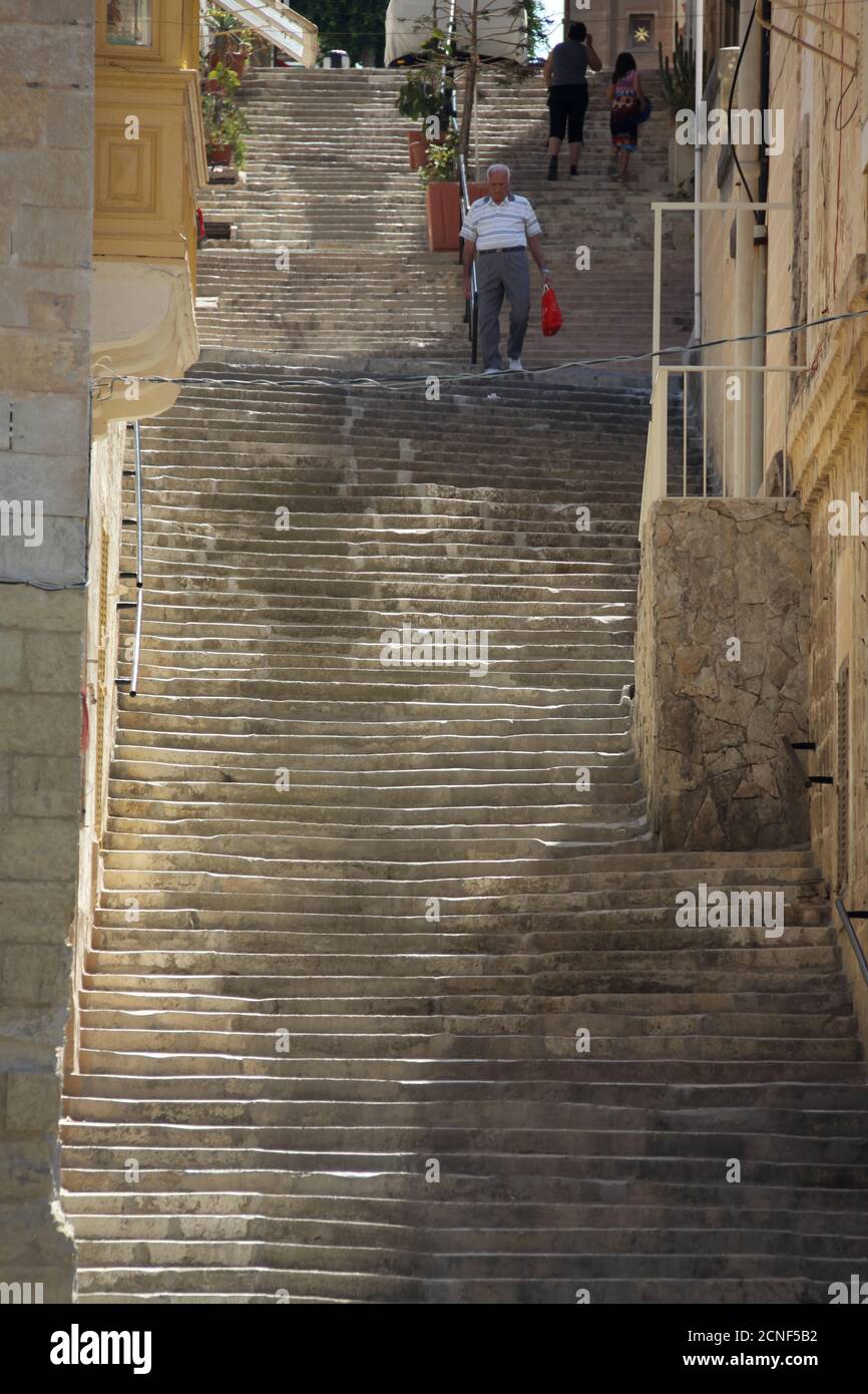 Man descending a long set of old stone steps in Birgu, Malta Stock ...