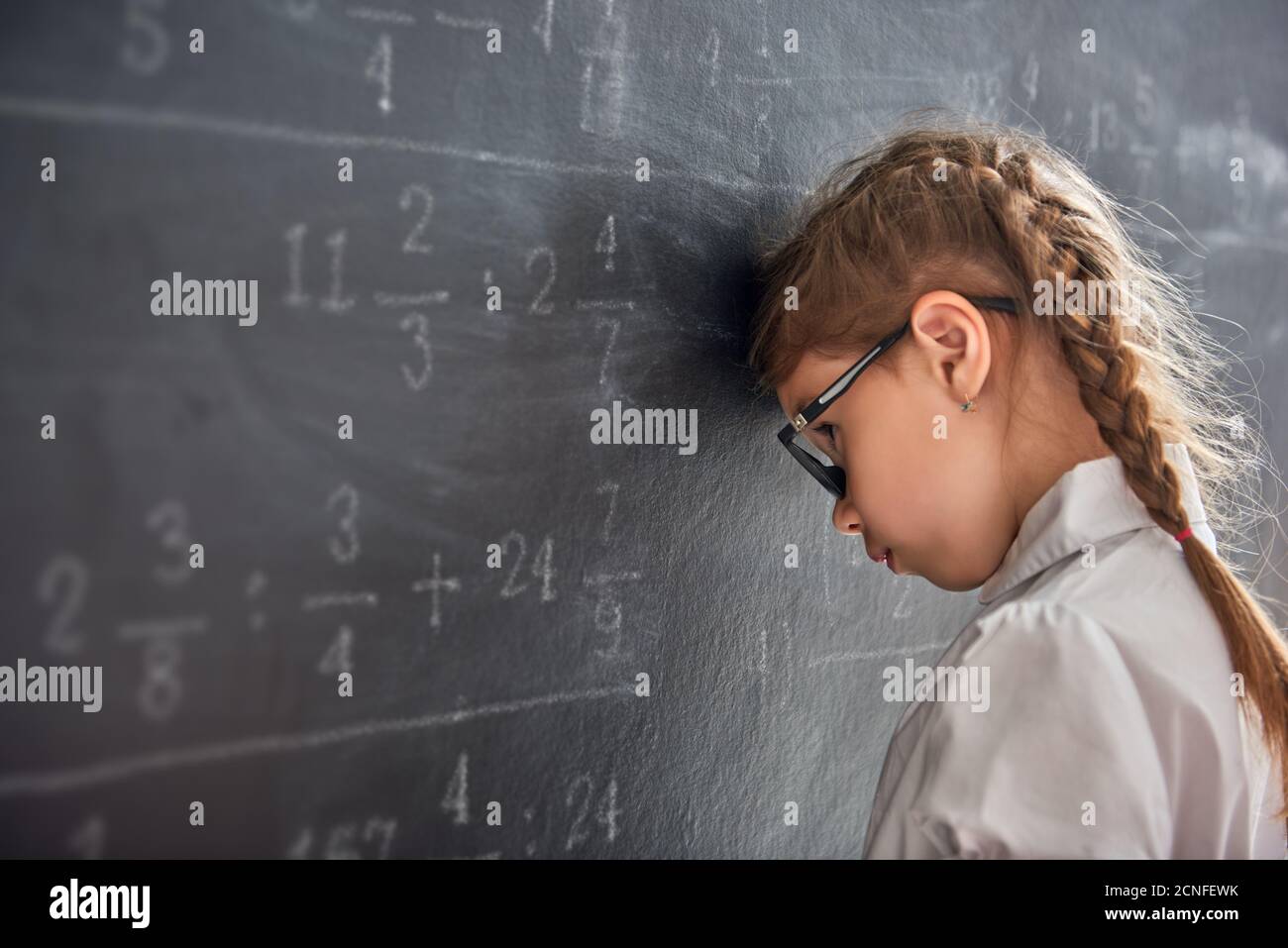 Tough day at school! Sad child near the blackboard indoors. Kid is ...