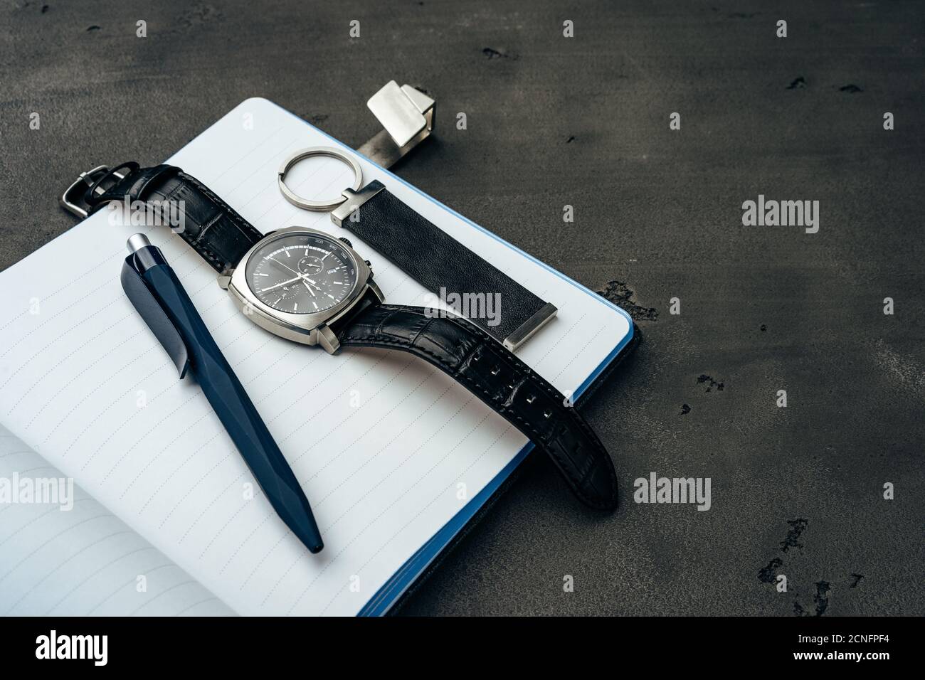 Male watch and notepad on dark grey table Stock Photo - Alamy