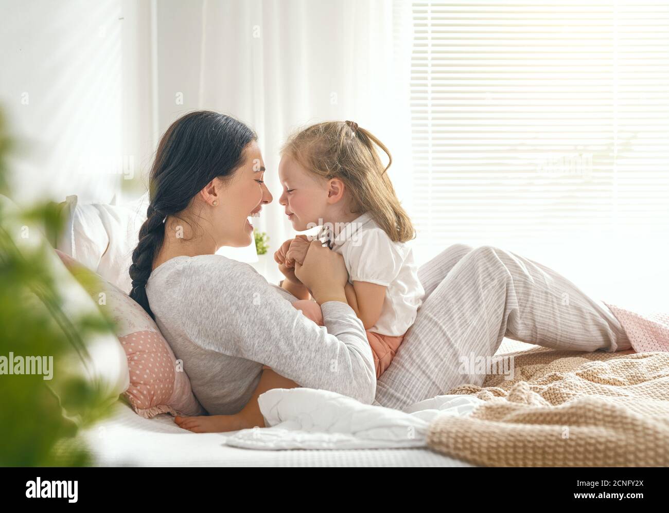A nice baby girl and her mother enjoy sunny morning. Good time at home ...