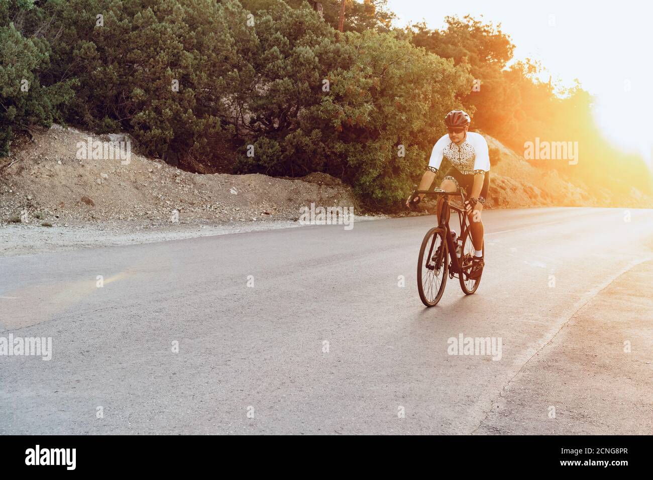 Man cyclist pedaling on a road bike outdoors in sun set Stock Photo - Alamy