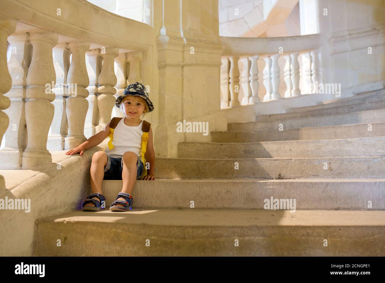 Little child, toddler boy, sitting on a stairs on big white staircasein ...